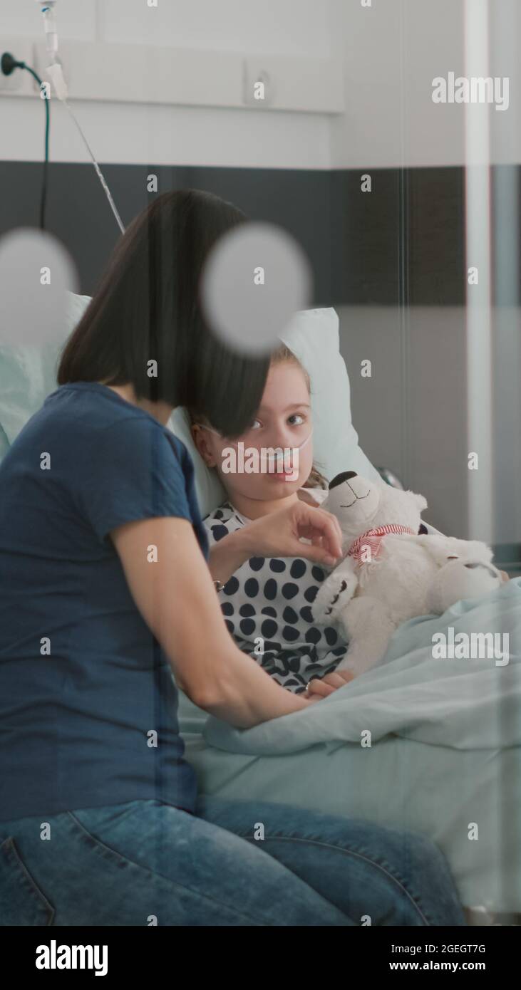 Hospitalized sick child resting in bed wearing nasal tube recovering ...