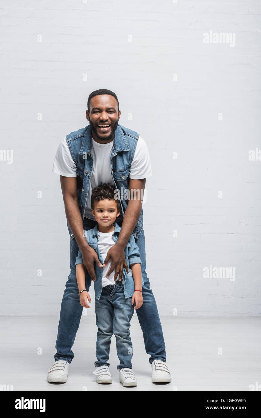 full length view of cheerful african american dad and son smiling at ...