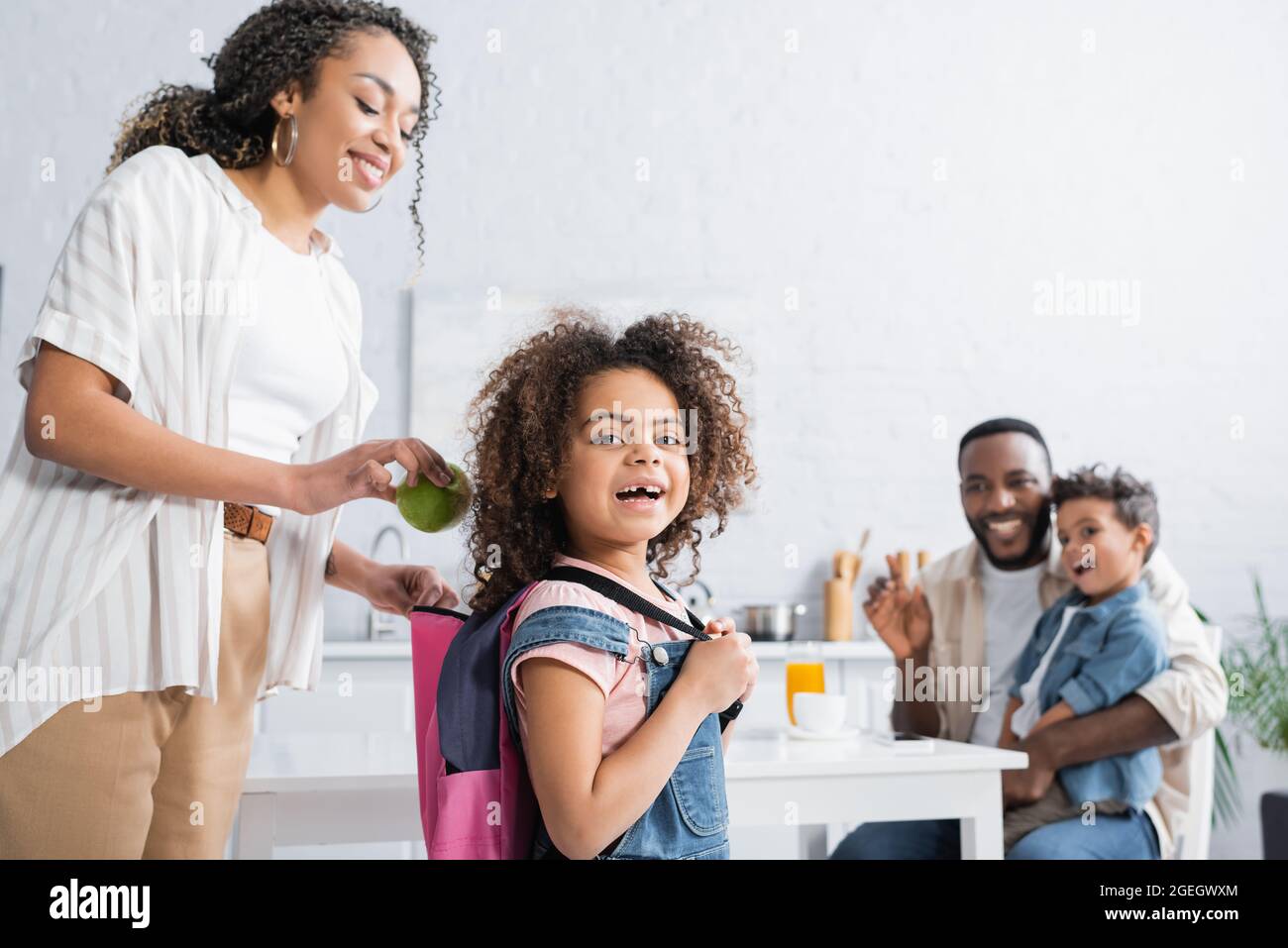 african american woman putting apple into backpack of daughter Stock ...