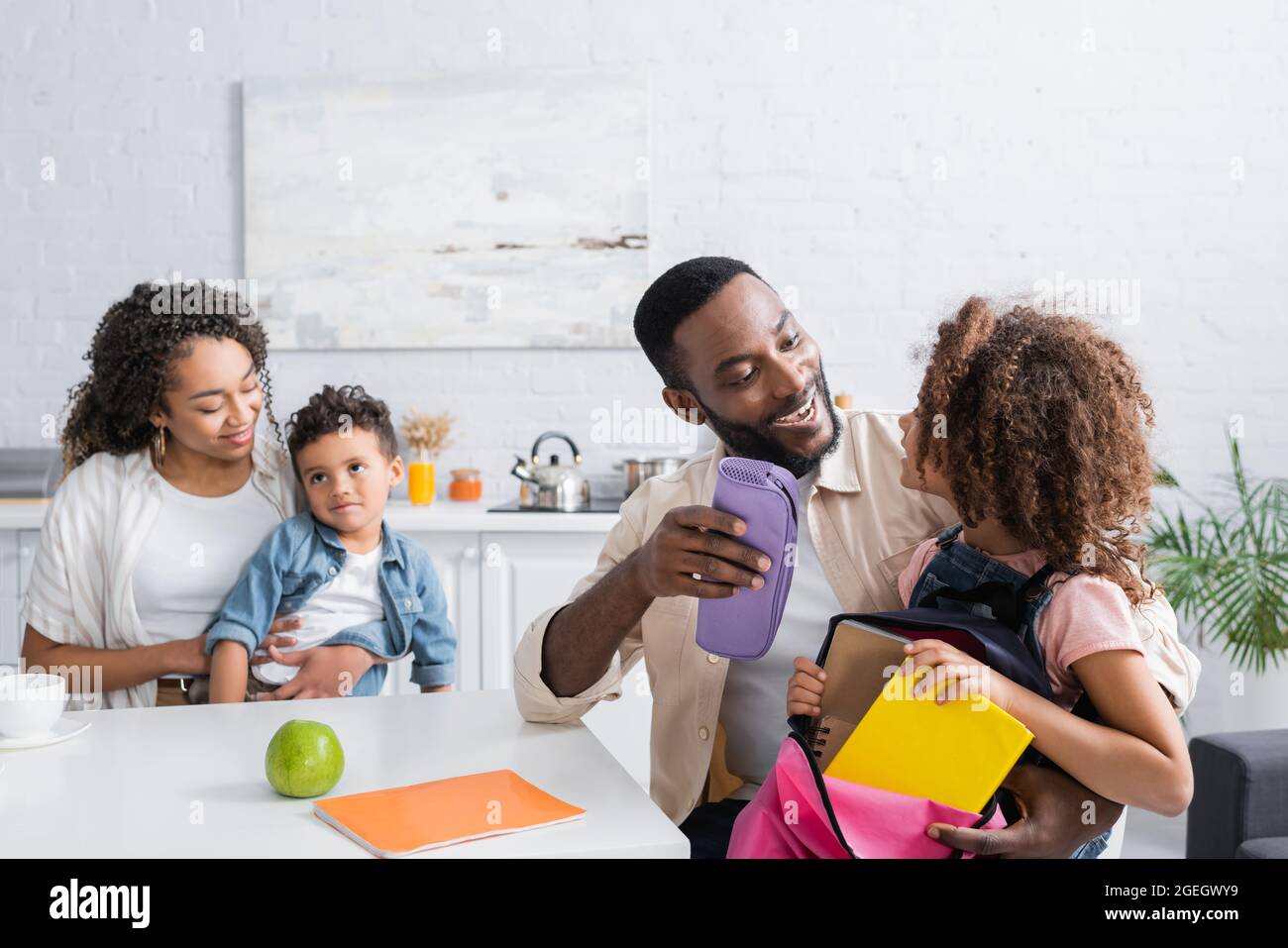 african american man packing backpack with daughter near family in ...
