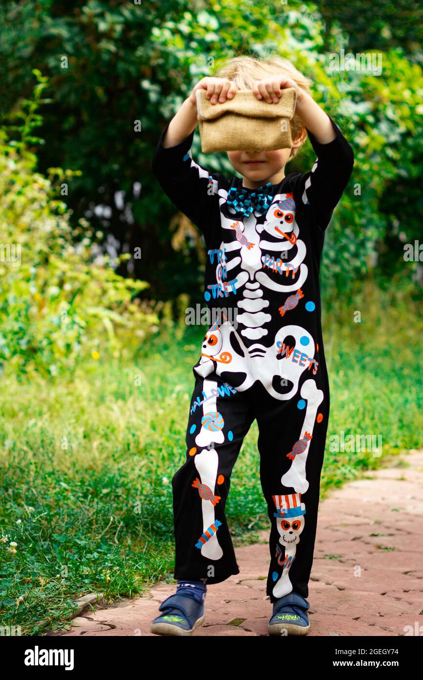 Little boy in skeleton costume holding a bag of chocolates for ...