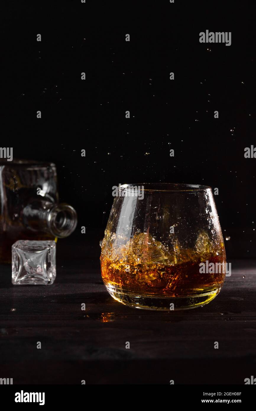 A glass of cognac with ice, splash, a decanter in the background ...