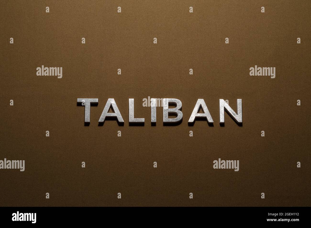 the word taliban laid with silver metal letters on tan khaki canvas ...