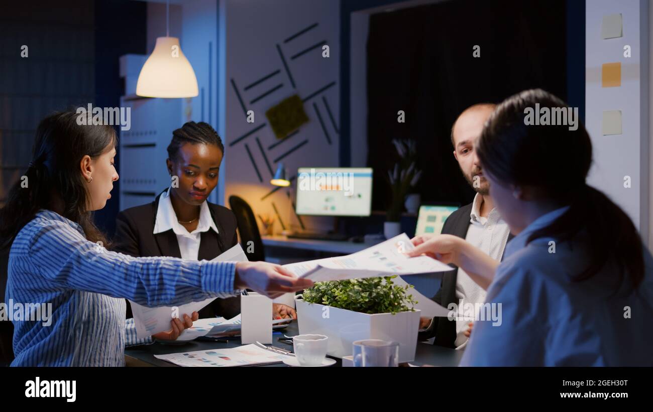 Diverse multiethnic businesspeople sharing management graphs paperwork ...