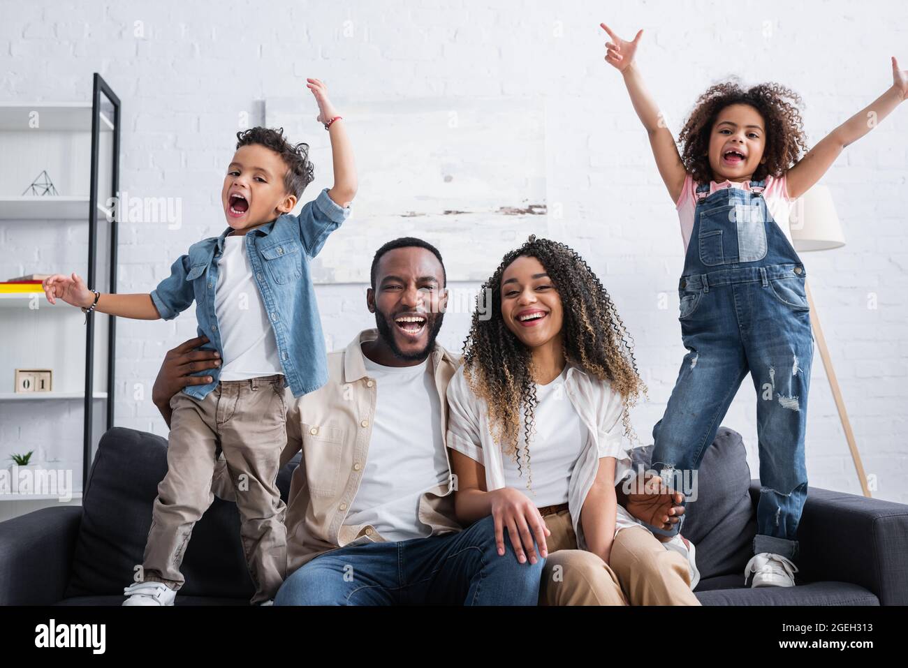 joyful african american children showing win gesture near happy parents ...