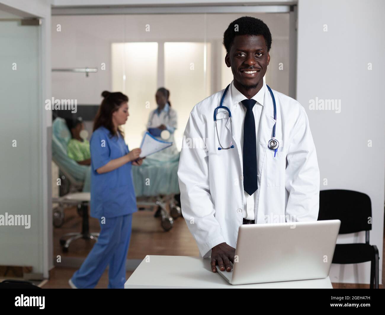 Portrait of african american man working at hospital ward desk with ...