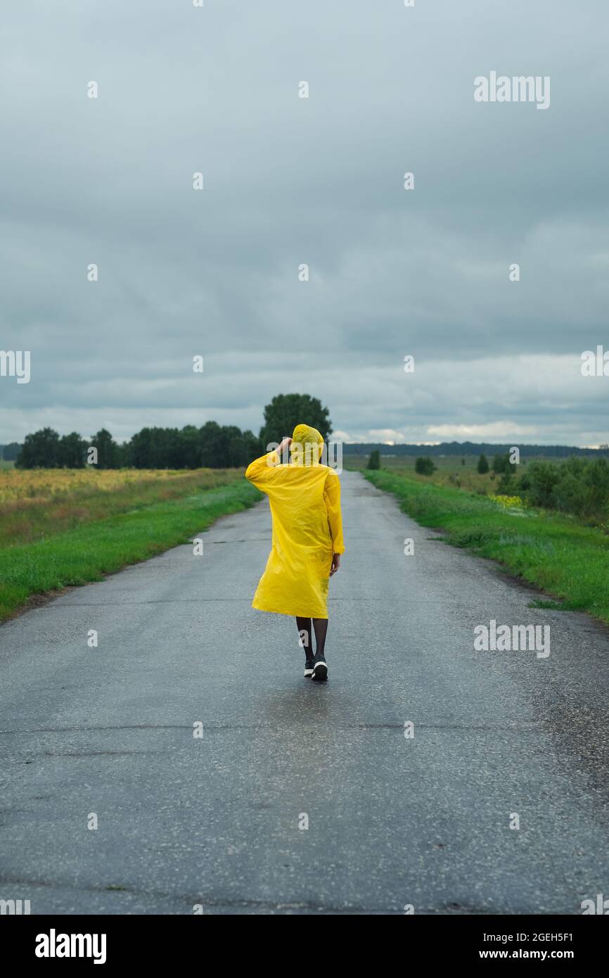 Back view of a female traveler in a yellow raincoat Stock Photo - Alamy