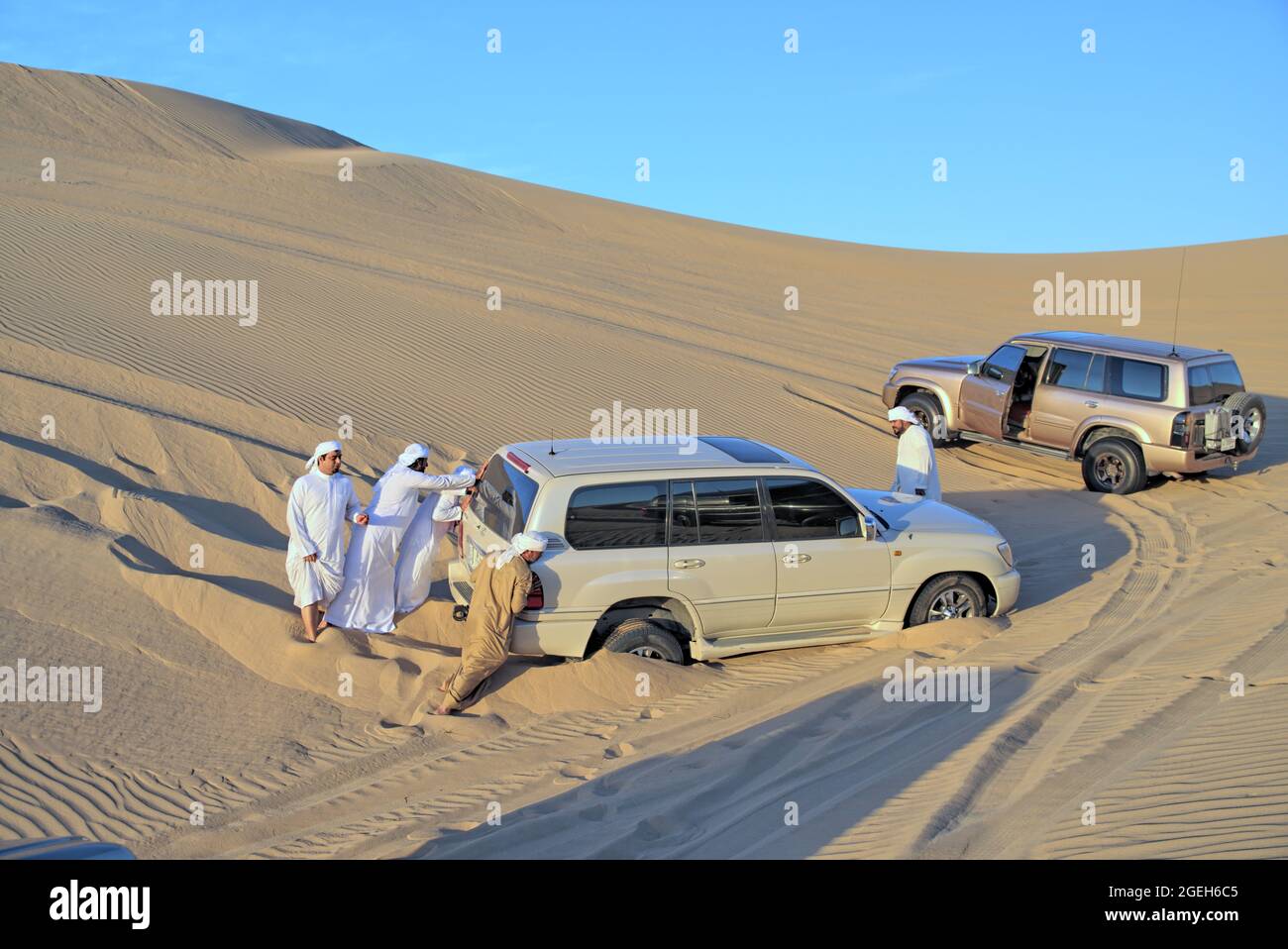Arab men pushing SUV car stuck in sand of desert Stock Photo - Alamy