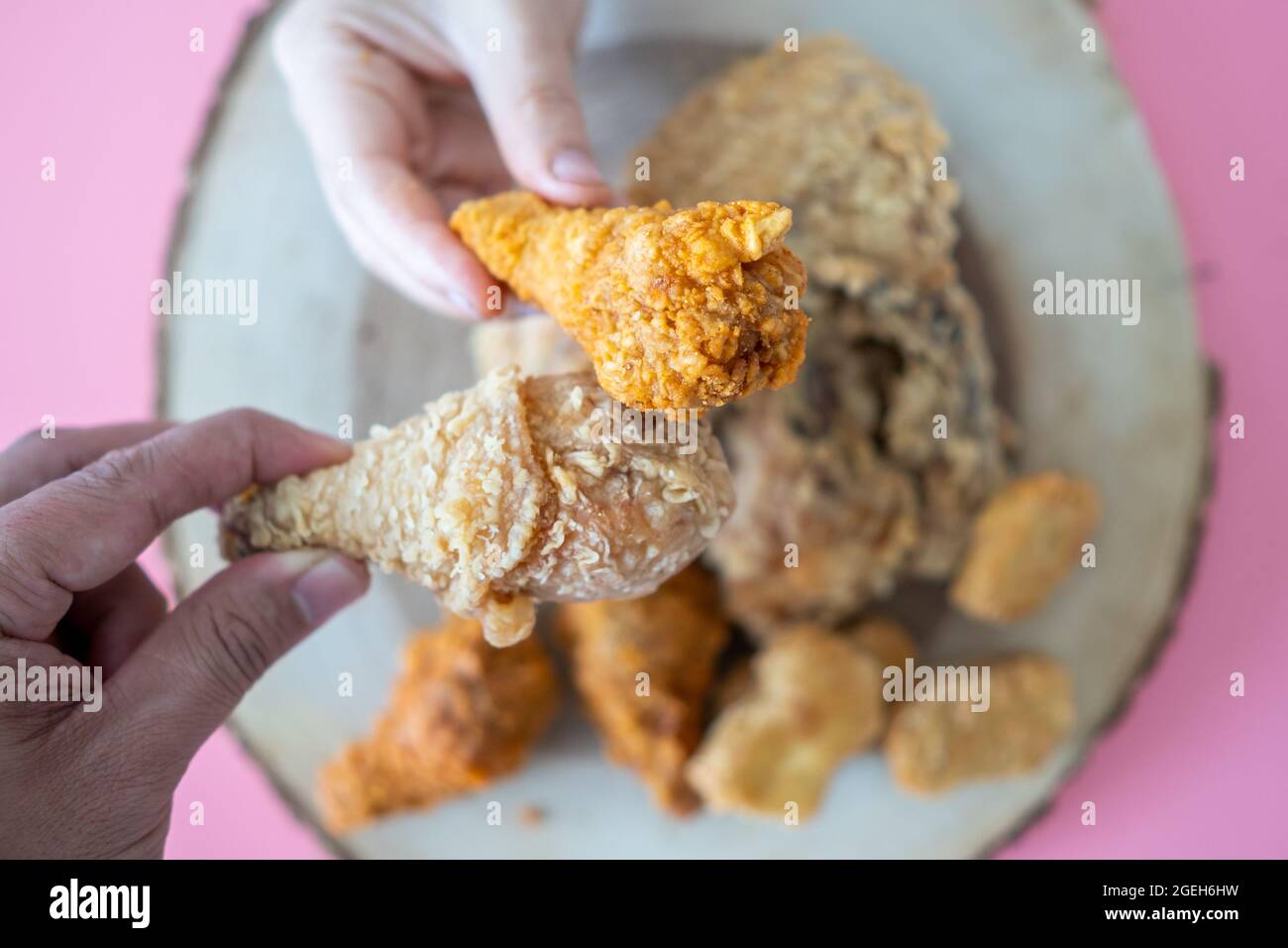 Overhead shot of a female and male hand taking fried chichen legs from ...