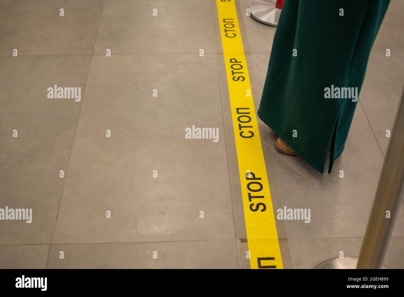 Female feet in boots at the yellow line on the floor with stop sign ...