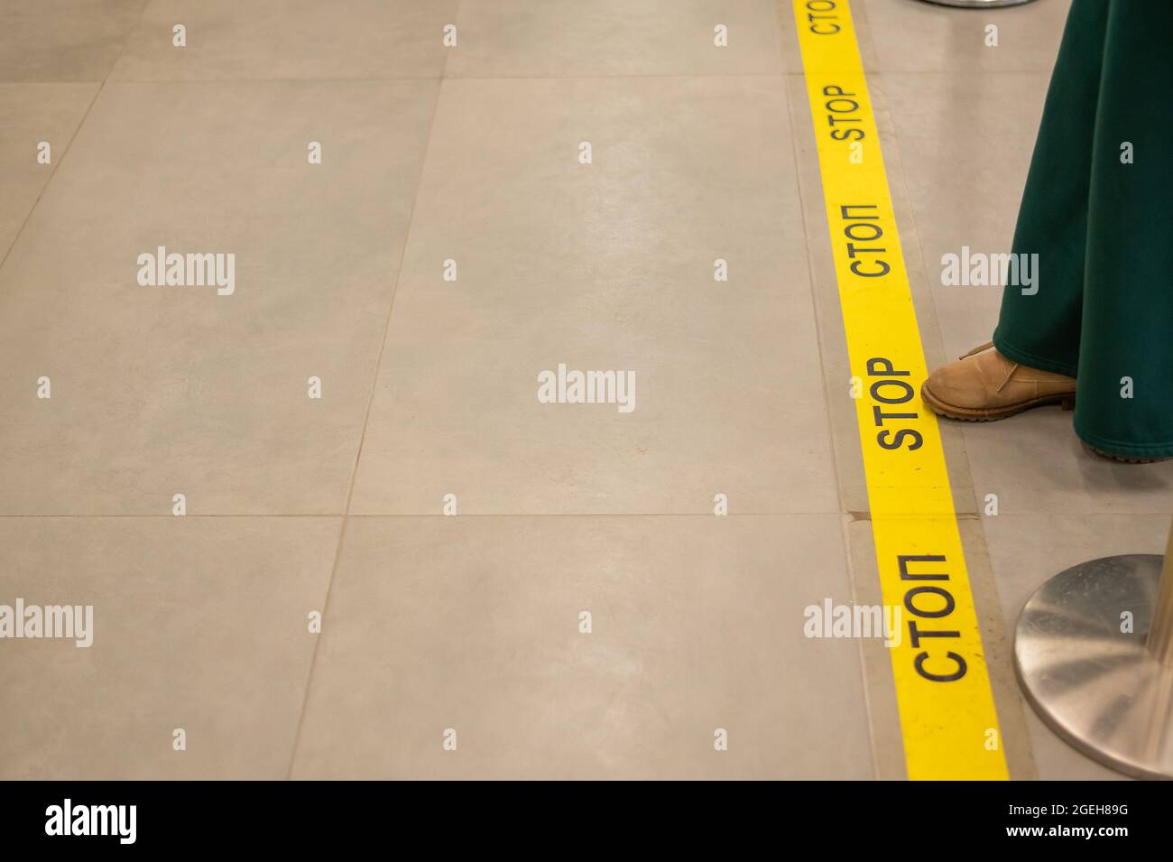 Female feet in boots at the yellow line on the floor with stop sign ...
