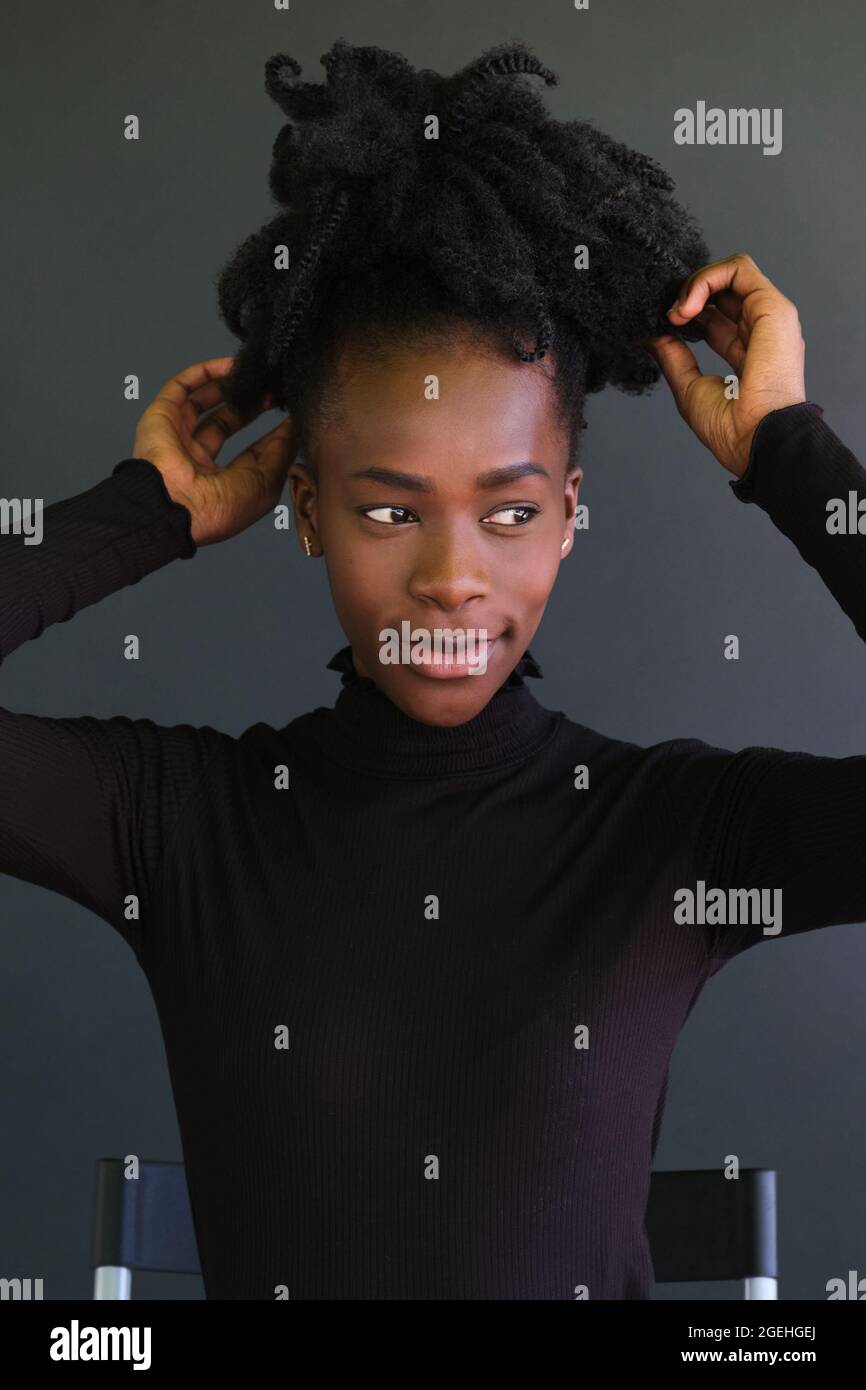Young african woman in black sweater sitting on a chair in a black ...