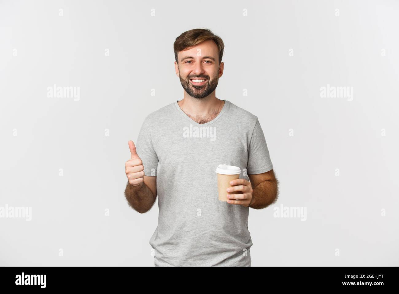 Portrait of cheerful caucasian man in gray t-shirt, drinking coffee and ...