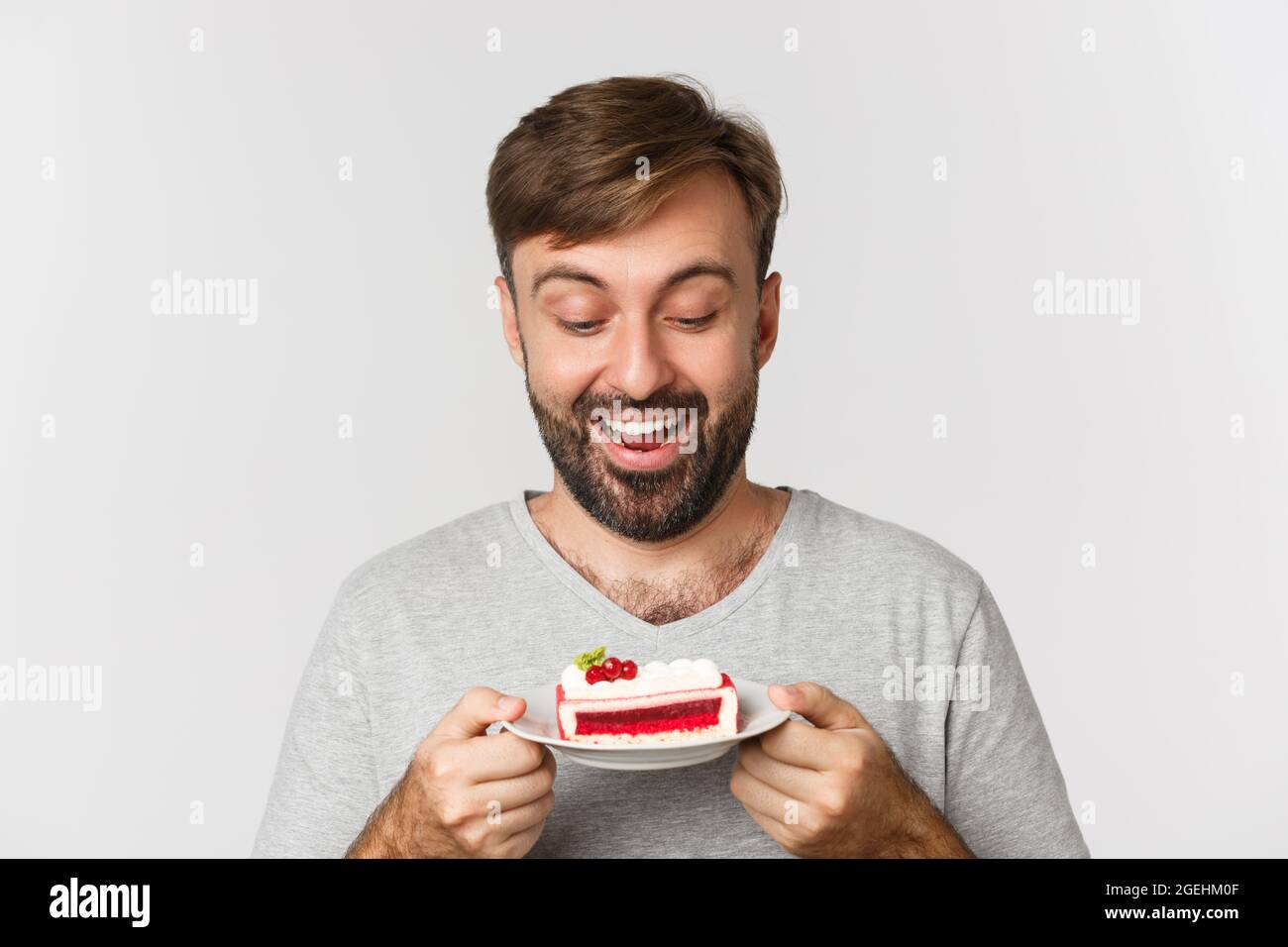 Close-up of handsome smiling man holding cake, standing over white ...