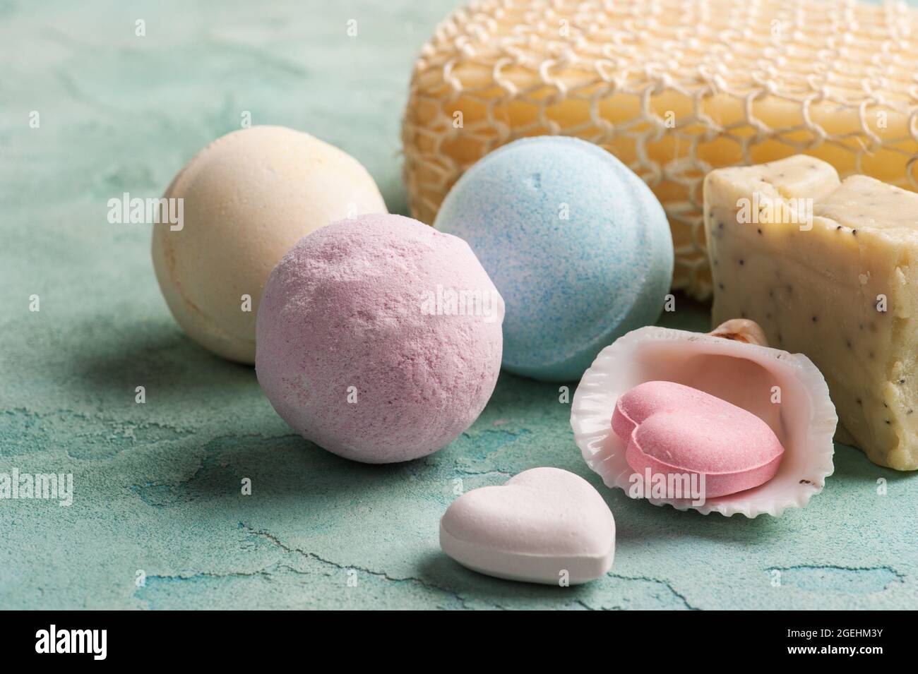SPA still life, pink heart shaped bath bombs in sea shell on turquoise ...