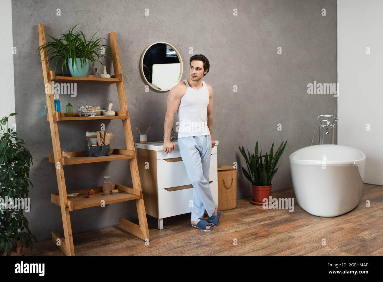 full length view of young man standing near sink in modern bathroom ...