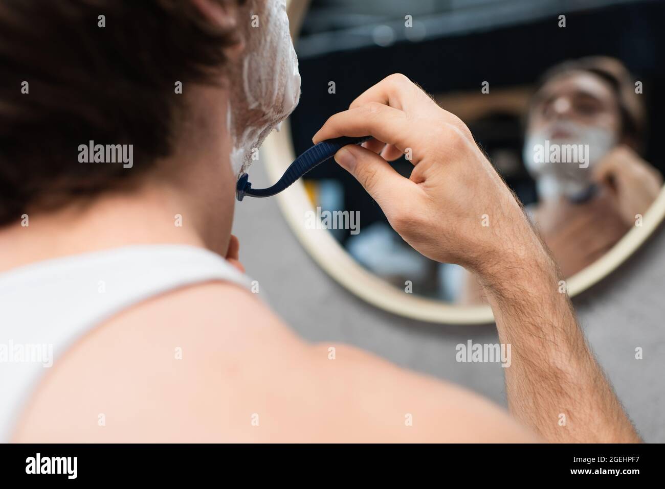 blurred man shaving with safety razor near mirror in bathroom Stock ...