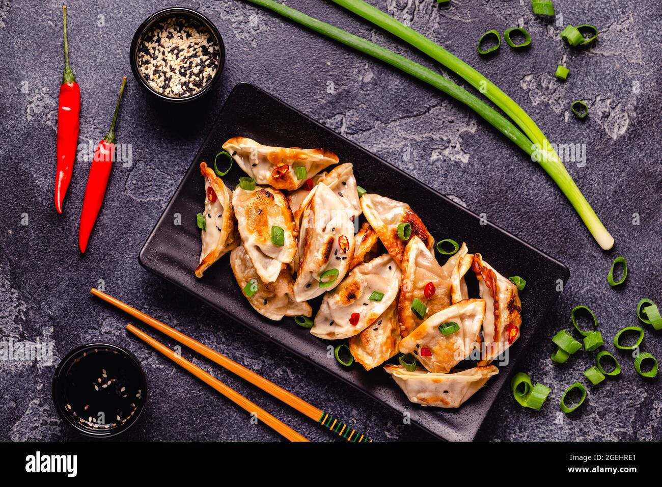 Fried dumplings served with green onions, sesame seeds and chili ...