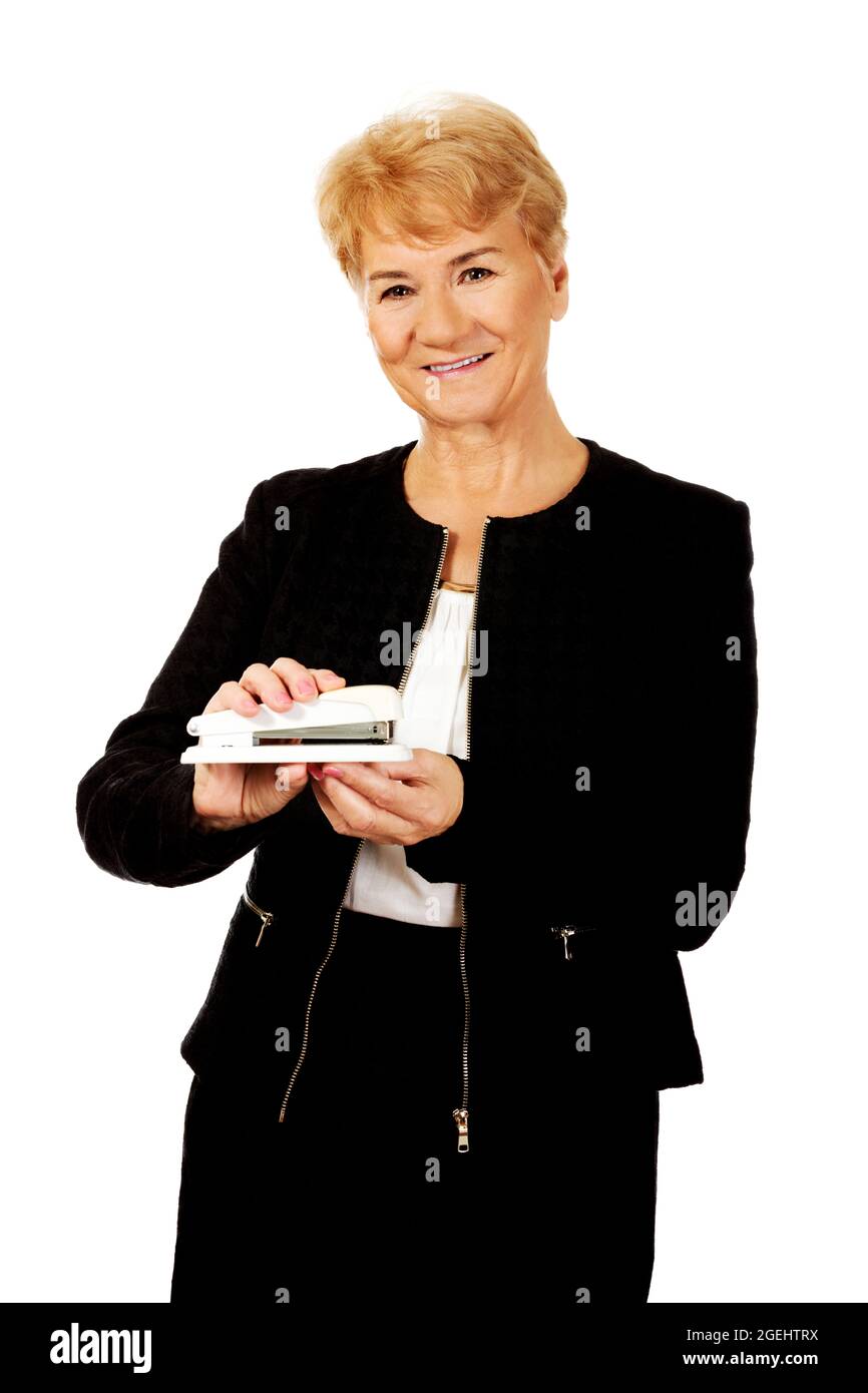 Senior Caucasian female office worker holding a stapler and smiling on ...