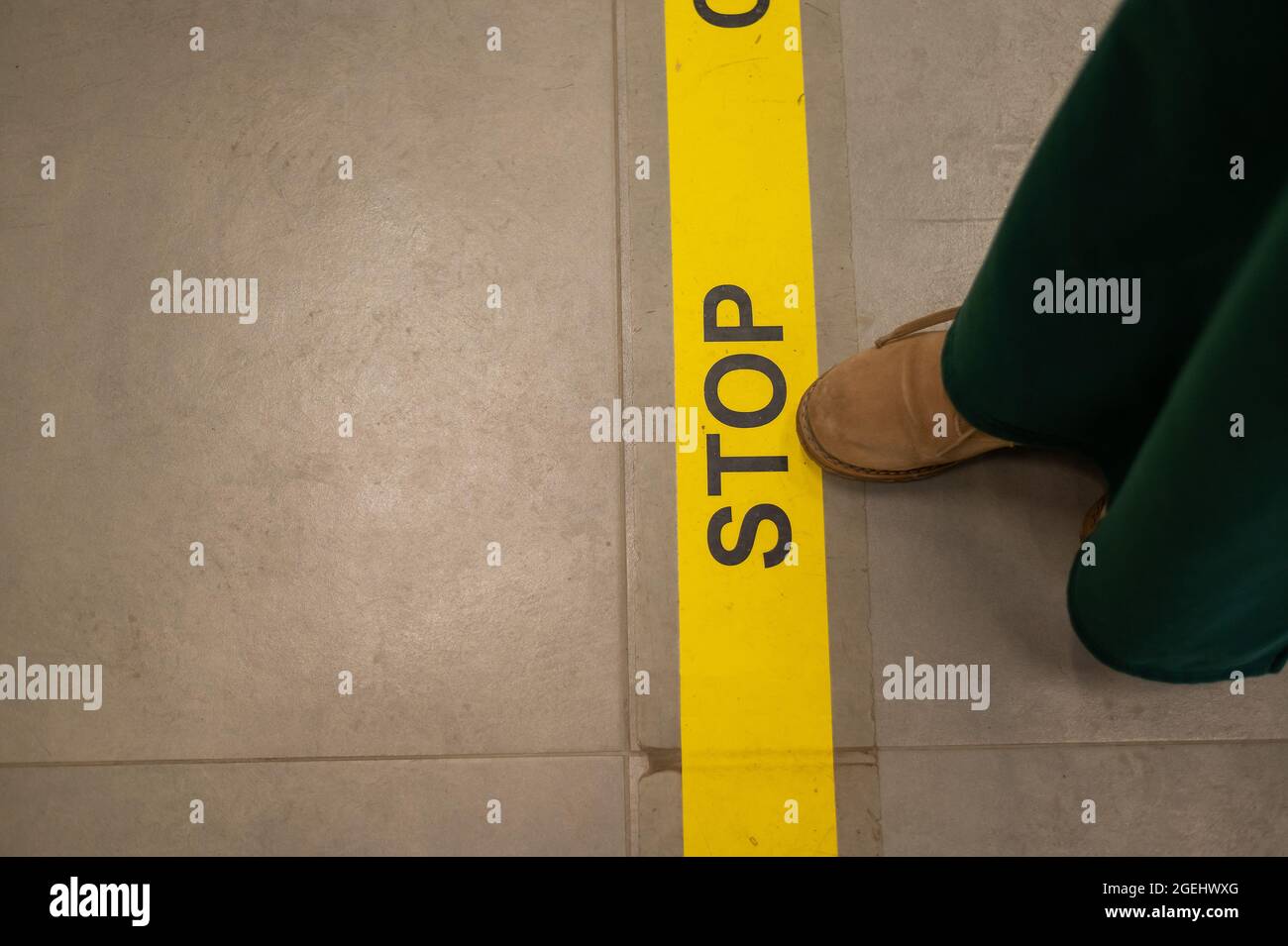 Female feet in boots at the yellow line on the floor with stop sign ...