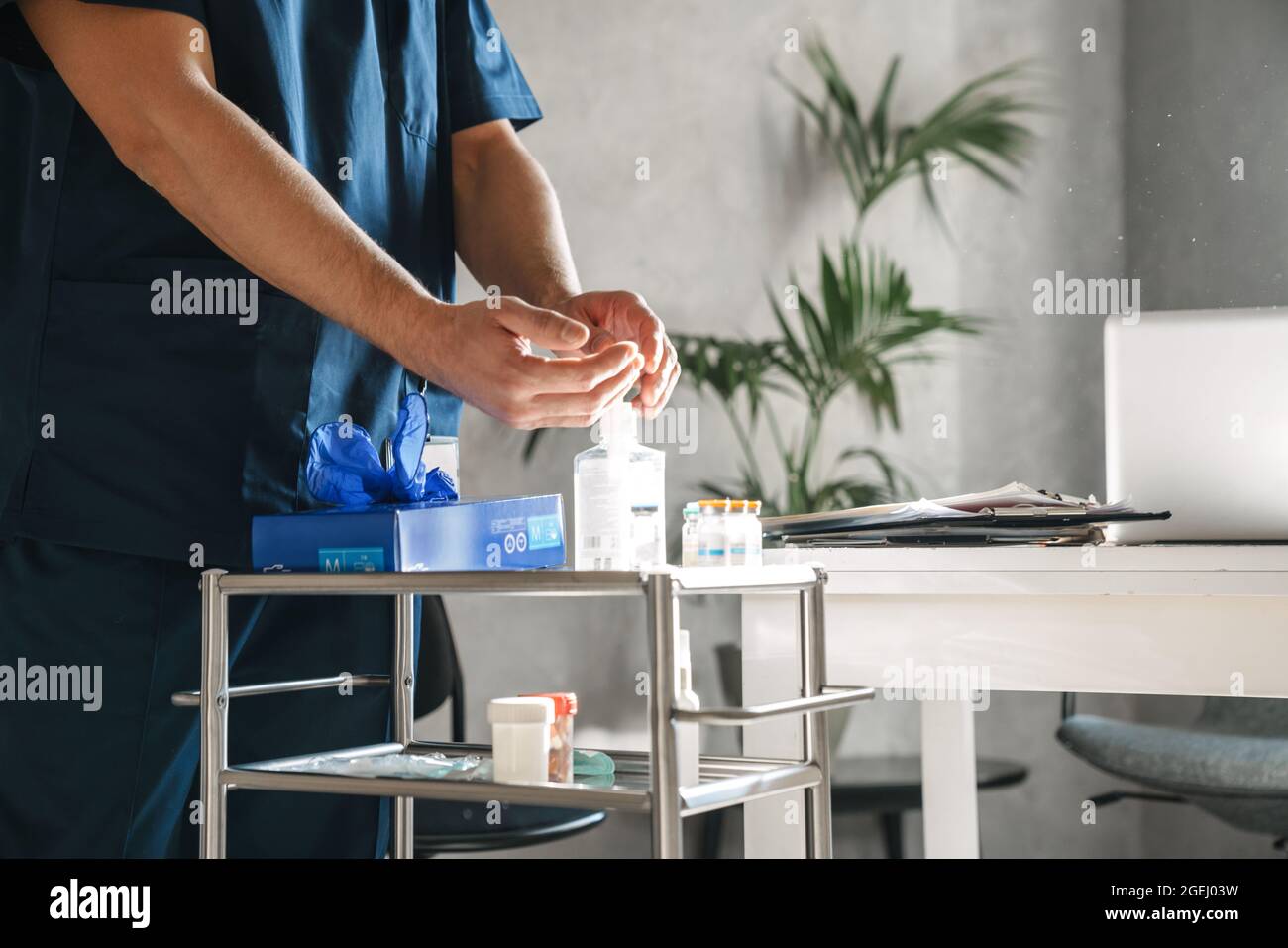 Male doctor sanitizing his hands before consulting patients in his ...