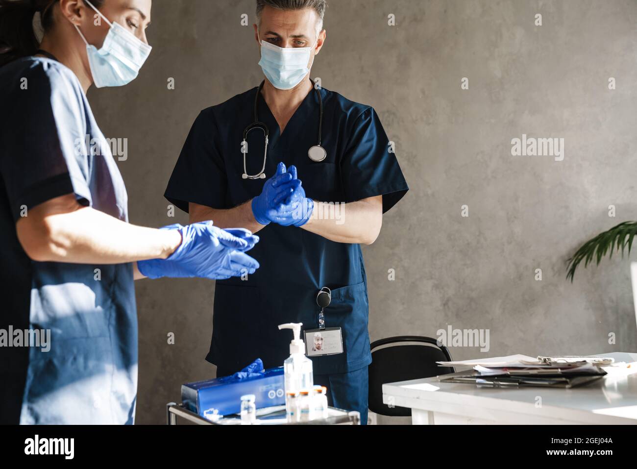 Two doctors getting ready to have patients in cabinet, putting gloves ...