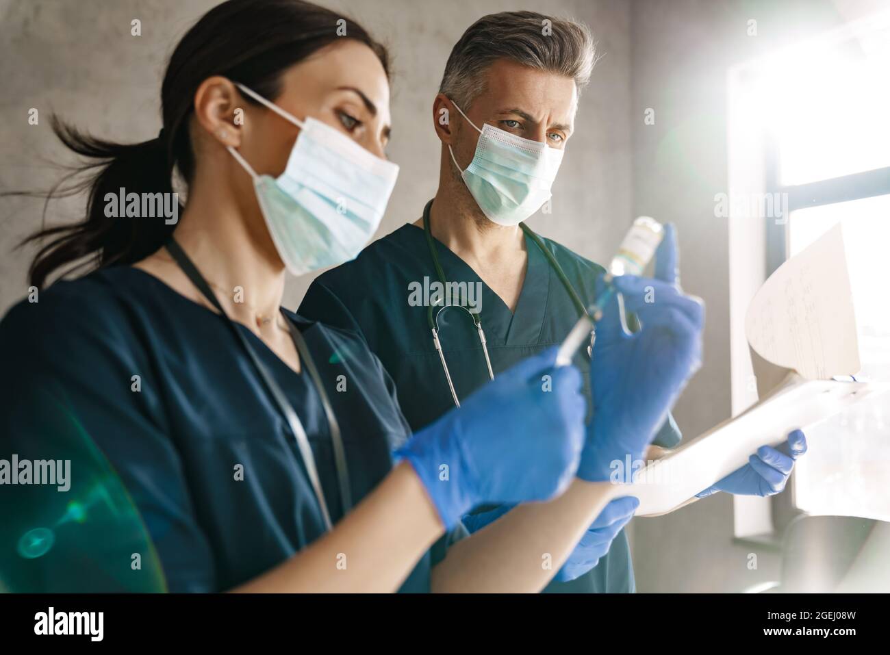 Two doctors getting ready to have patients in cabinet, holding syringe ...