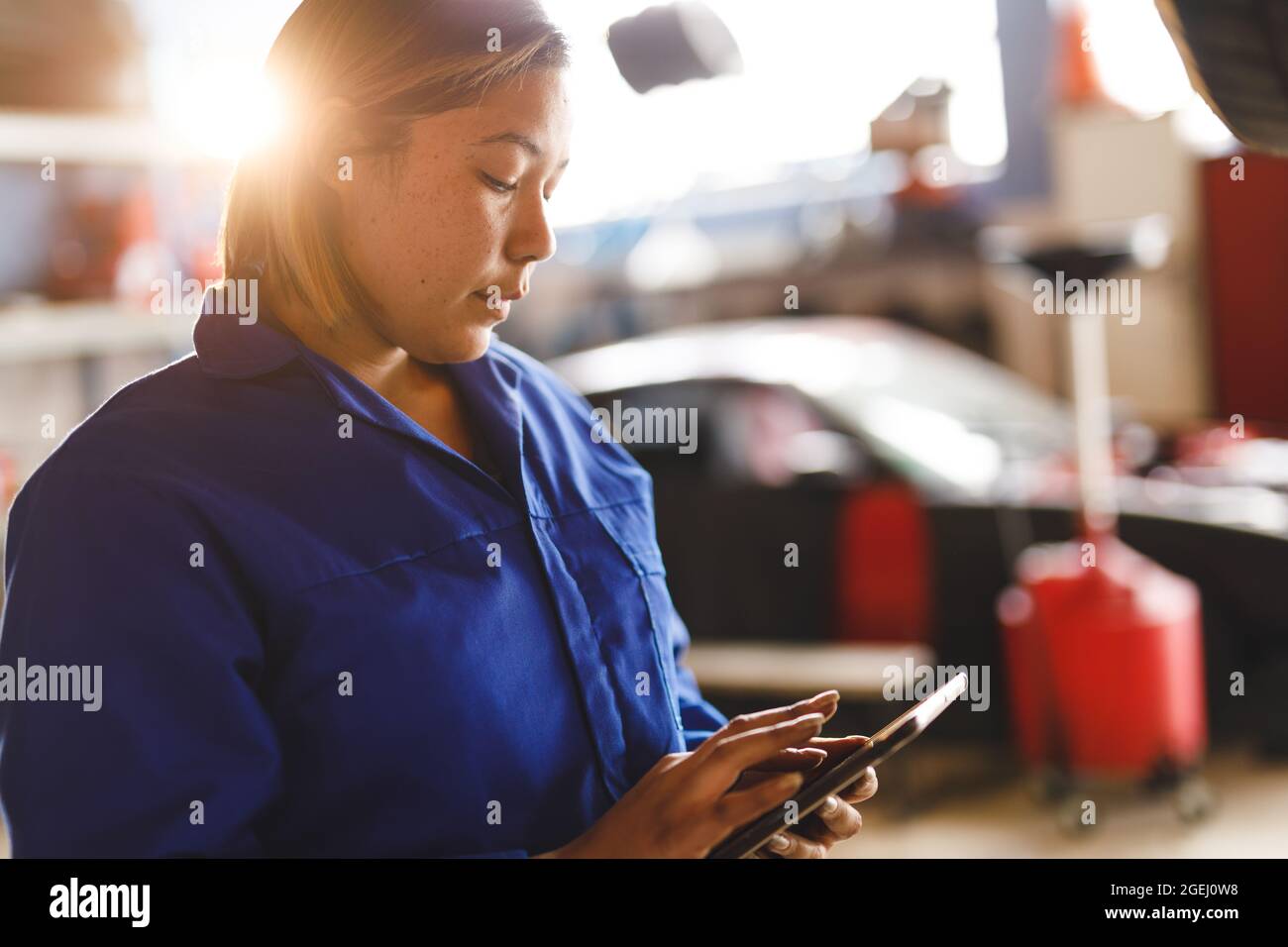 Mixed race female car mechanic wearing overalls, using tablet Stock ...
