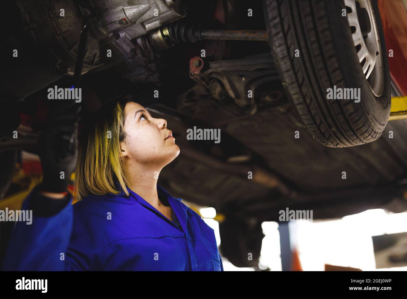 Mixed race female car mechanic wearing overalls, inspecting car Stock ...