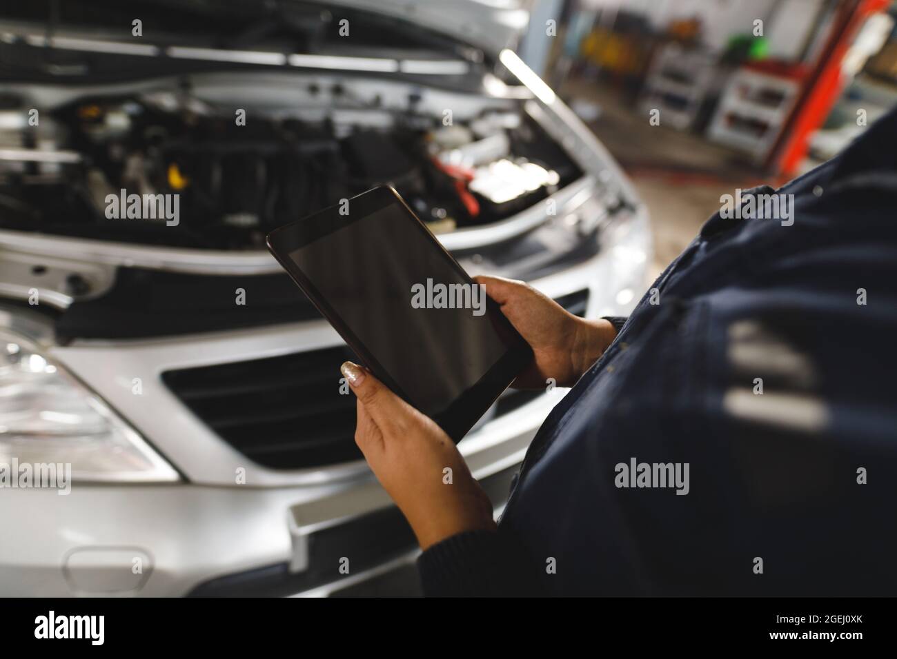 Close up of hands of mixed race female car mechanic wearing overalls ...