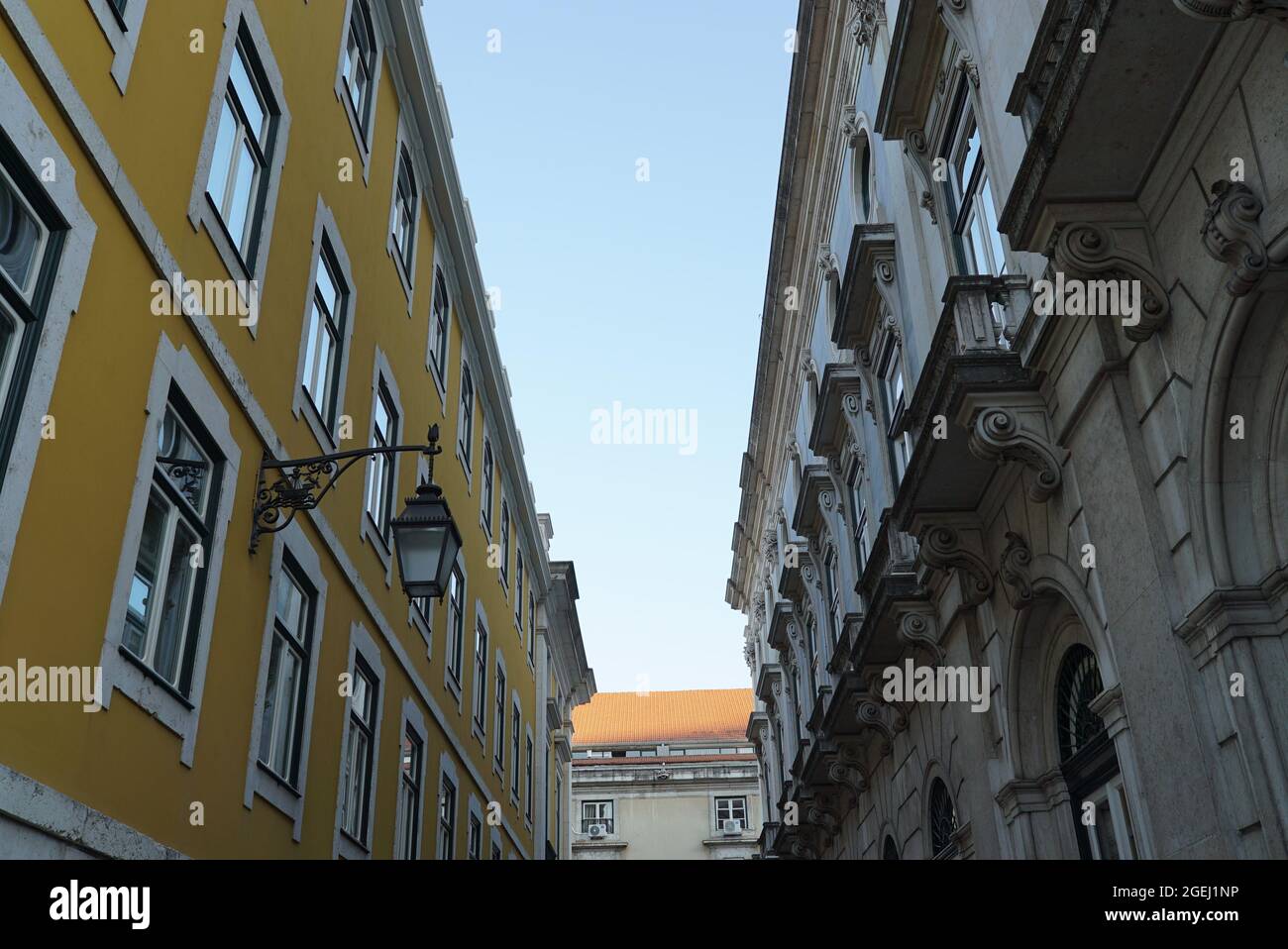 Low angle of passage between yellow and gray buildings against under ...