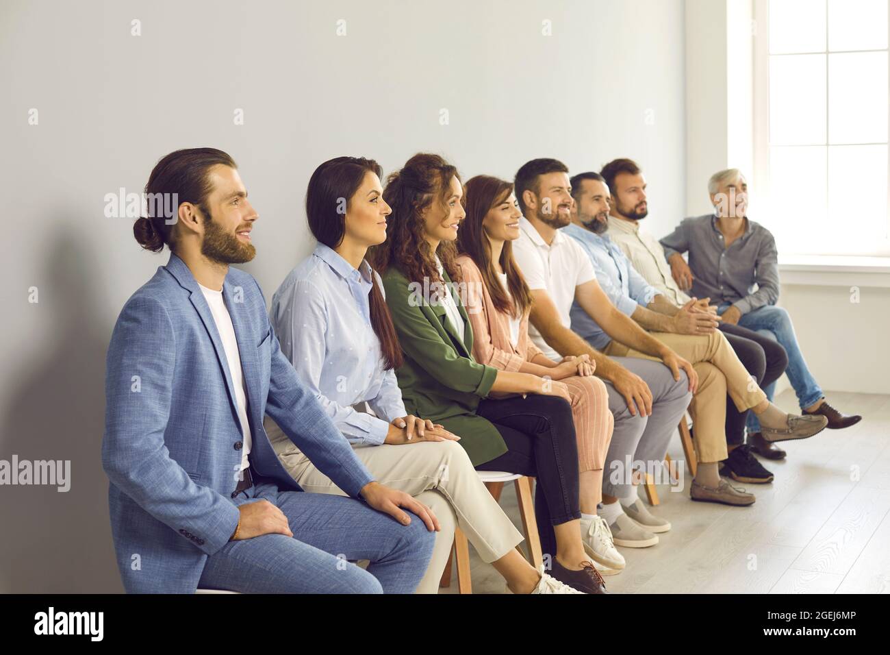 Concentrated happy business people listening intently sitting in a row ...