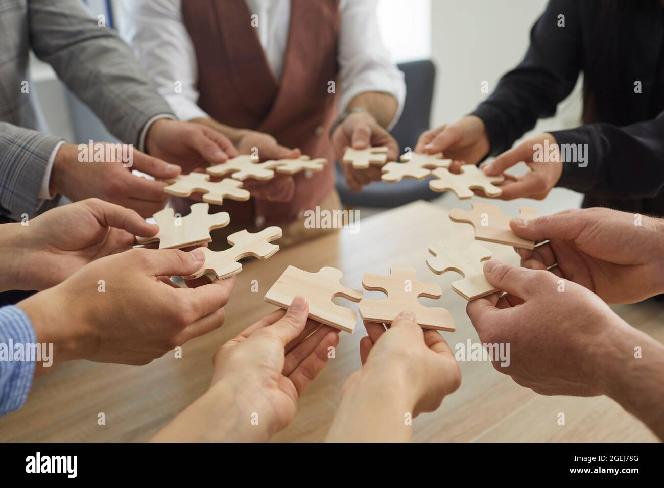 A group of business people holding and putting together pieces of a ...