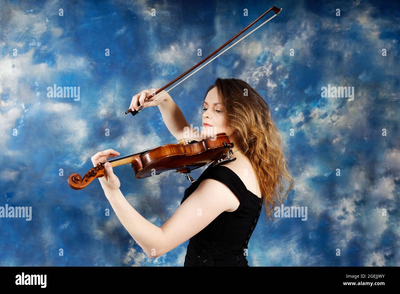 Young woman playing the violin against abstract blue background Stock ...
