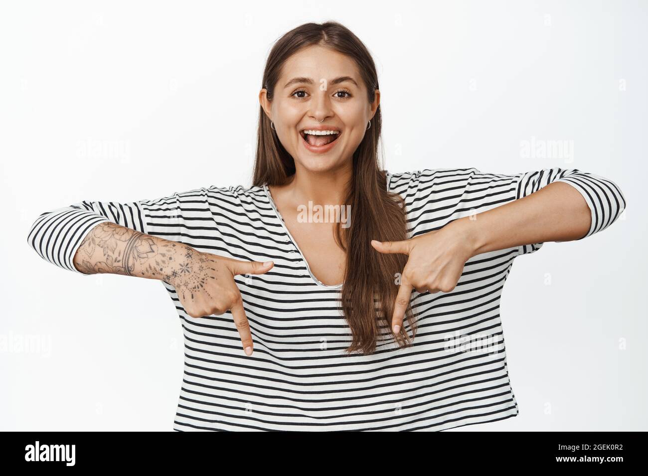 Hey look below. Smiling young woman pointing fingers down with happy ...