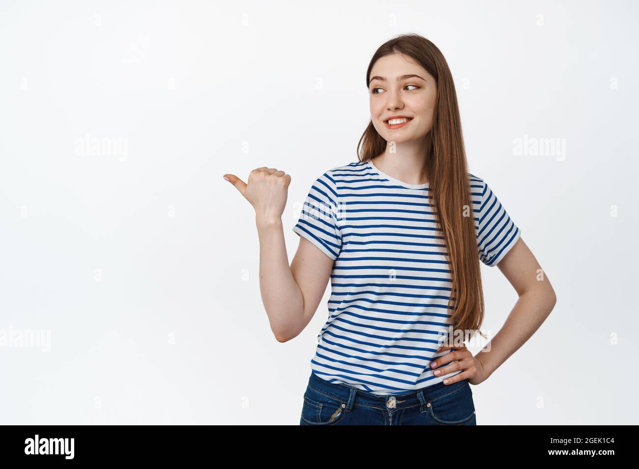 Young smiling woman, pointing and looking left with relaxed, happy face ...