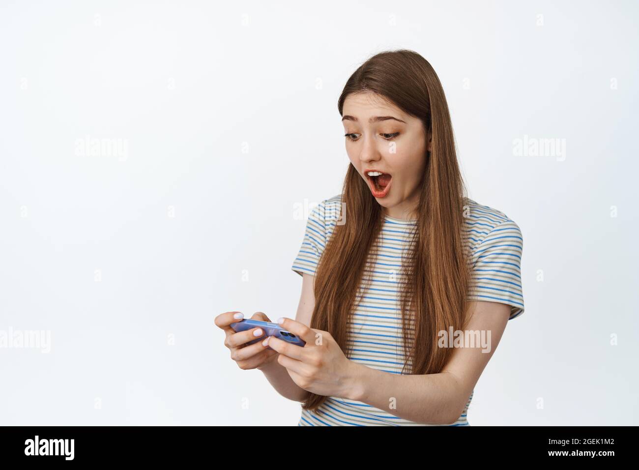 Woman looks surprised at mobile phone screen. Girl reacts to smth ...