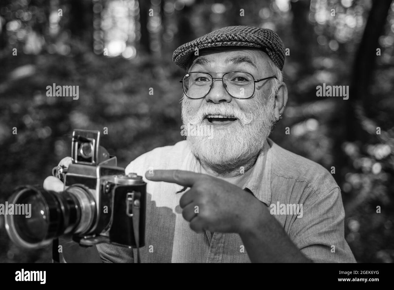 Look at this. Old photographer pointing at retro camera. Bearded man ...