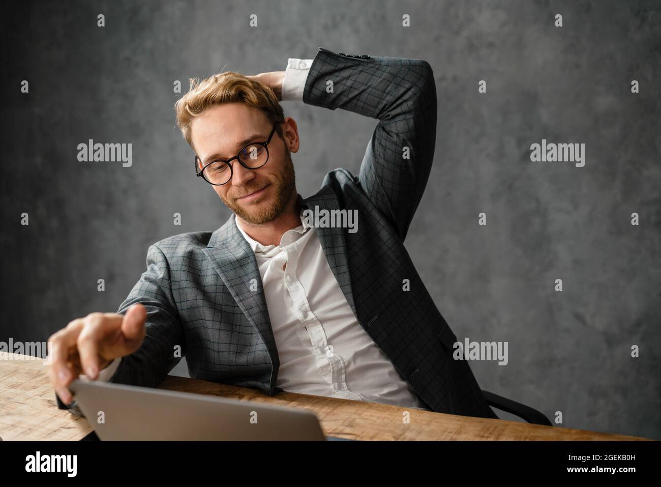 The smiling man in glasses looking into the laptop screen while holding ...