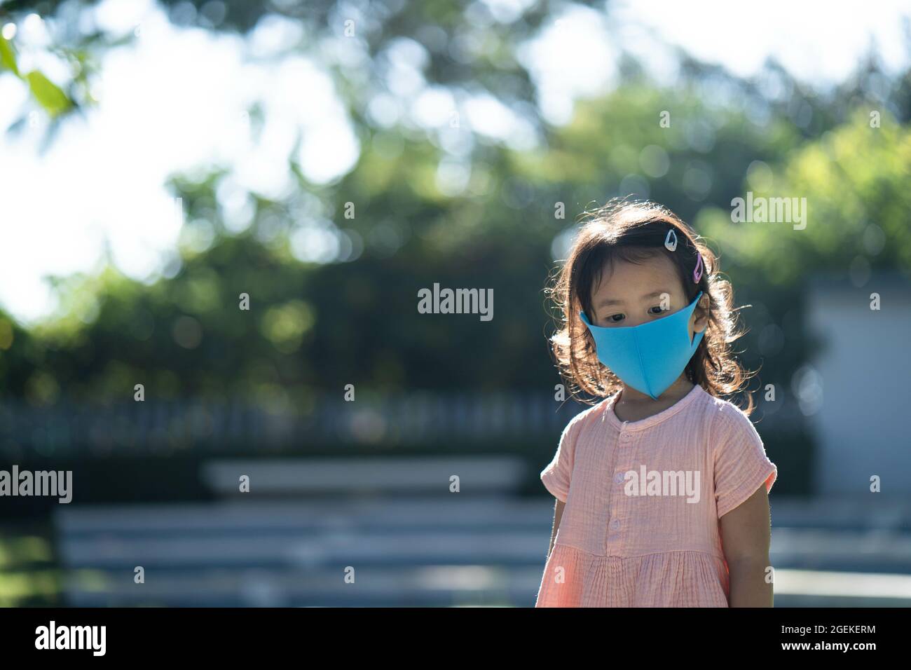 Beautiful Southeast Asian female kid with a mask on her face in the ...
