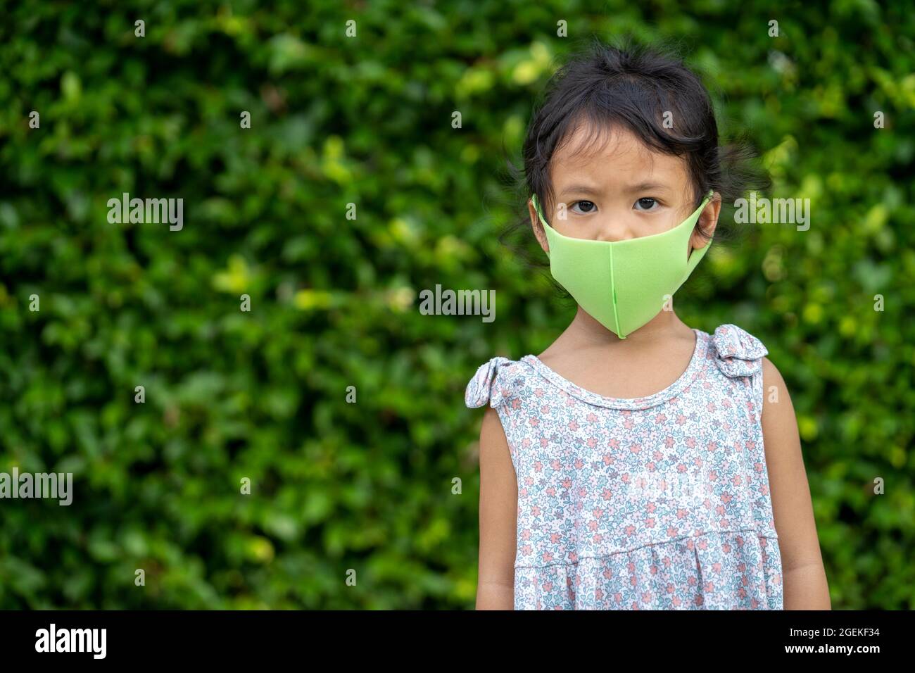 Beautiful Southeast Asian female kid with a mask on her face standing ...