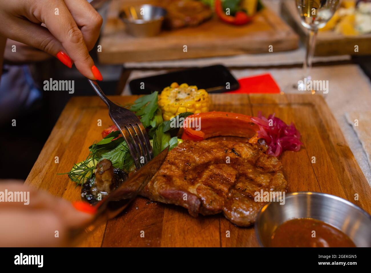 Young woman eating grilled steak in restaurant Stock Photo - Alamy