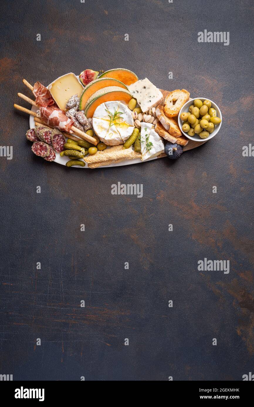 Assorted cheeses on wooden board plate, olive, grapes, bread on black ...