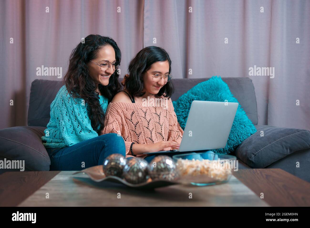 Horizontal view of a mom and daughter using a laptop, the two are happy ...