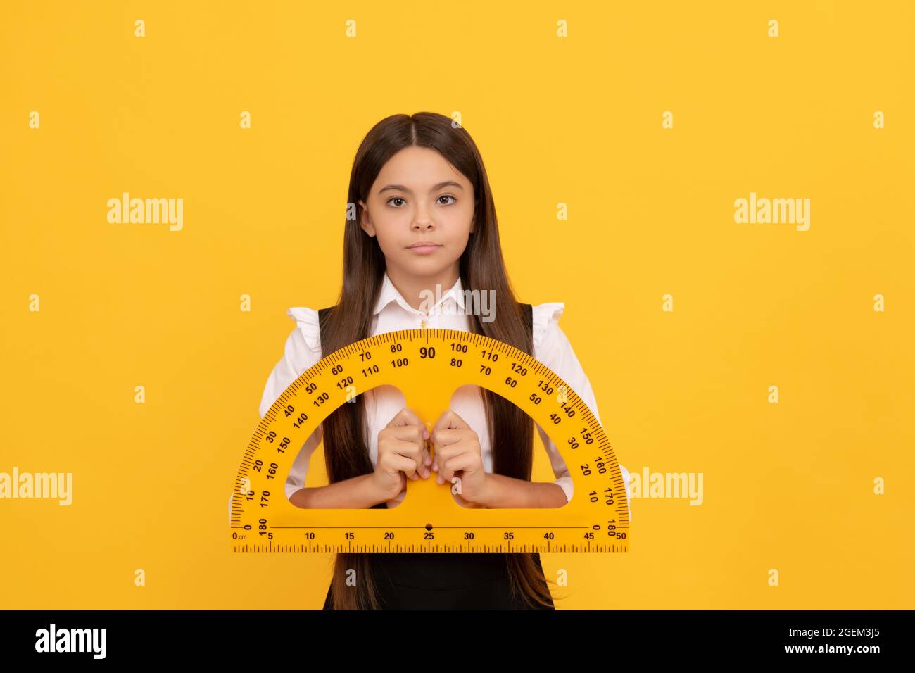 serious child in school uniform hold mathematics protractor for ...