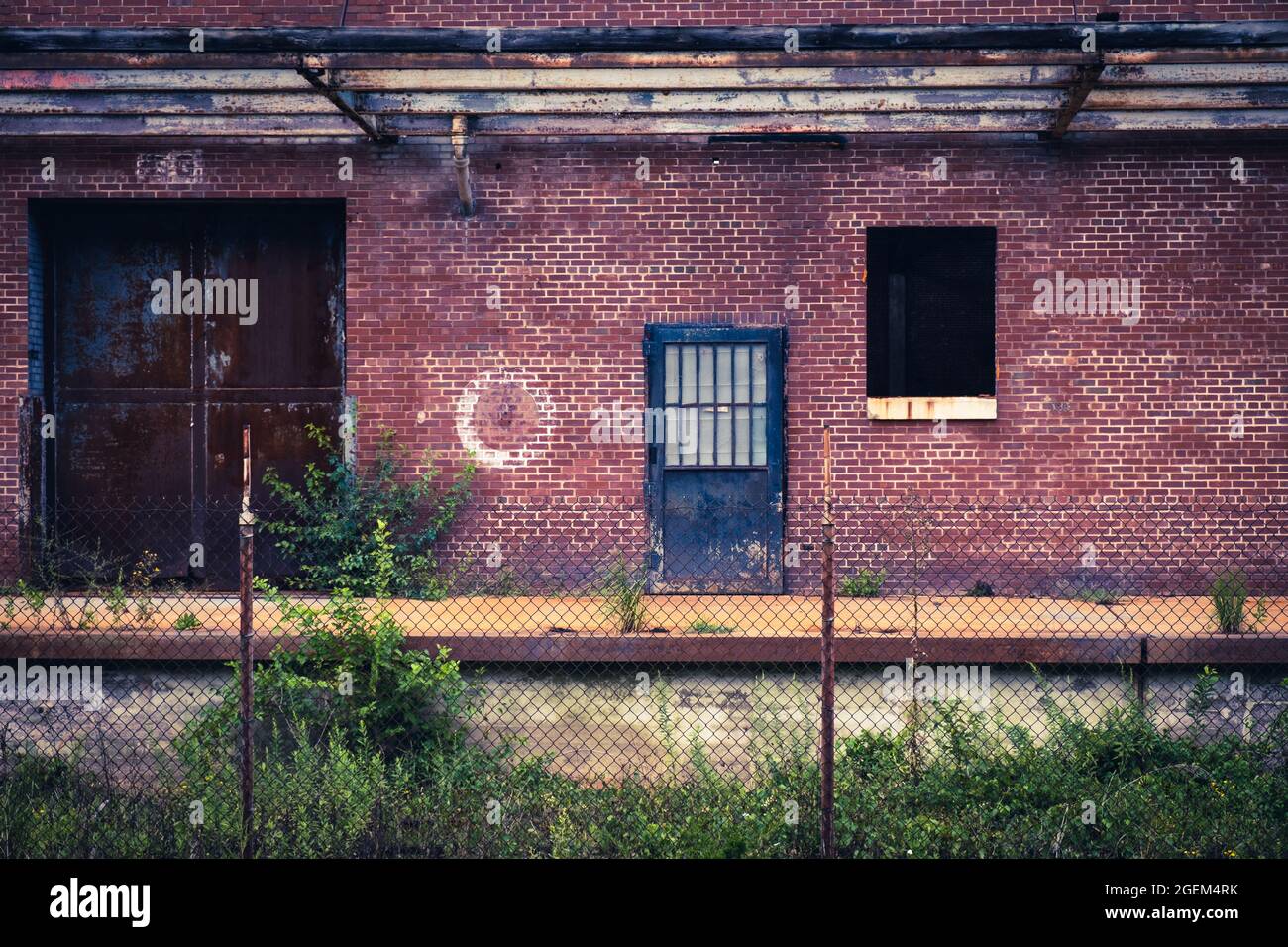 Old factory doors set in brick wall on abandoned loading dock with ...