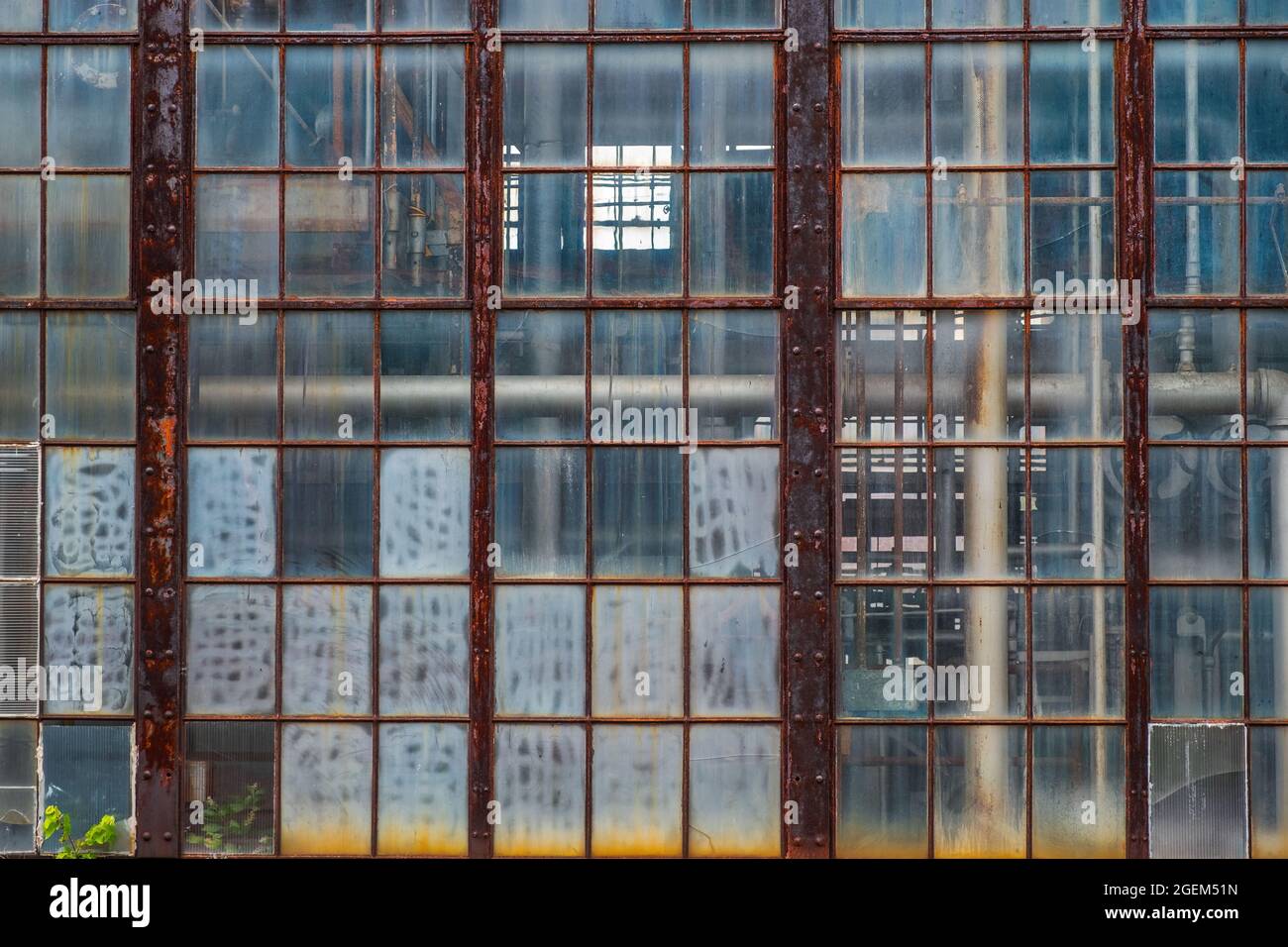 Old industrial pipes seen through grungy window panes at Camp North End ...