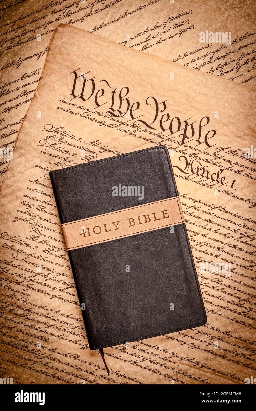 A holy bible and a small cross rest atop the United States Constitution ...