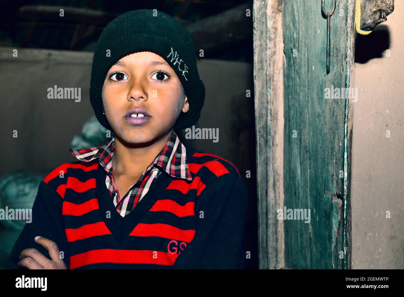 The Indian rural child is standing near the door of his house wearing a ...