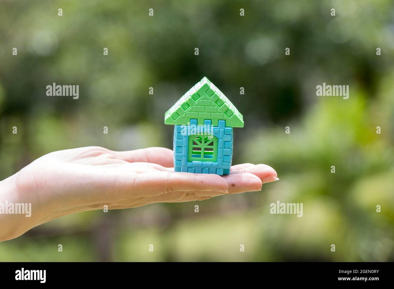 Woman hand hold home block model with blur green background (Concept ...